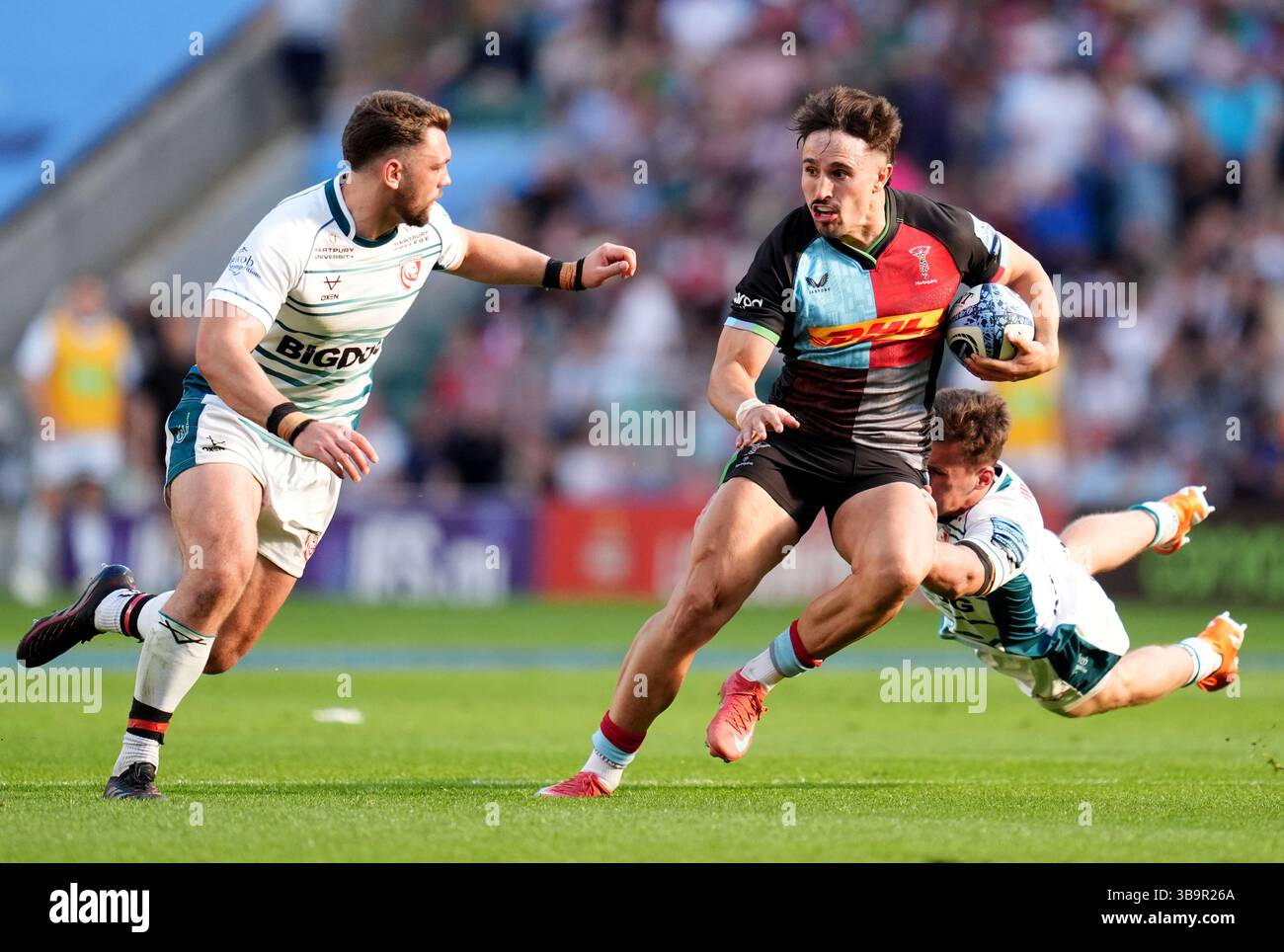 Harlequins' Cadan Murley (centre) breaks a tackle before running in to ...