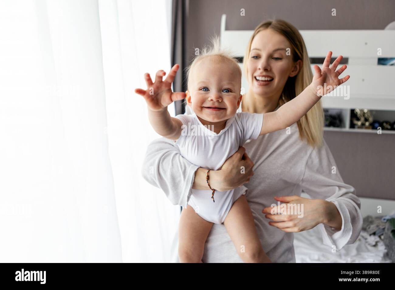 Happy baby girl reaching toward camera while being held by smiling ...