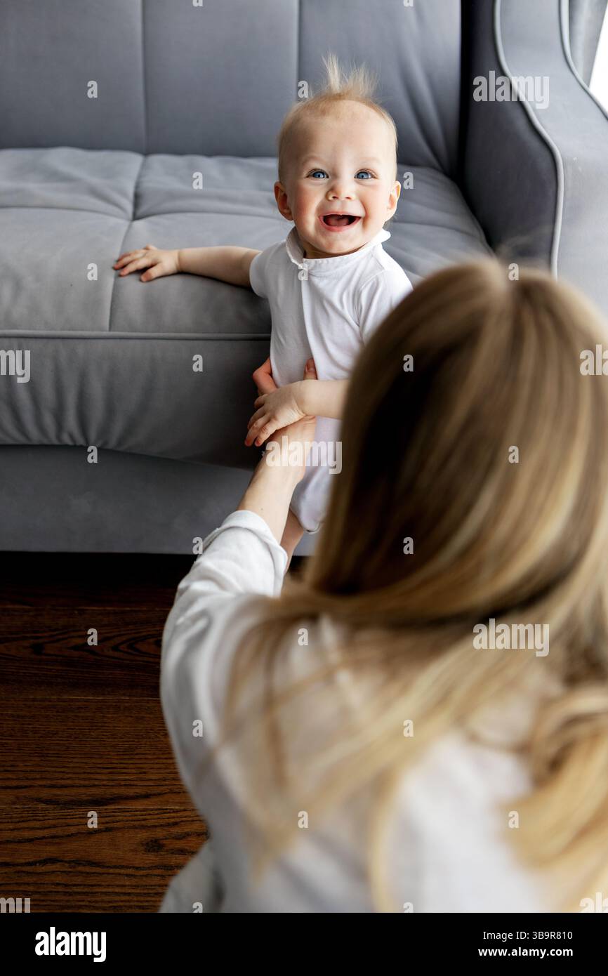 Mother and baby at home. Mom helping Child take first steps, emotional and heartwarming moment ...
