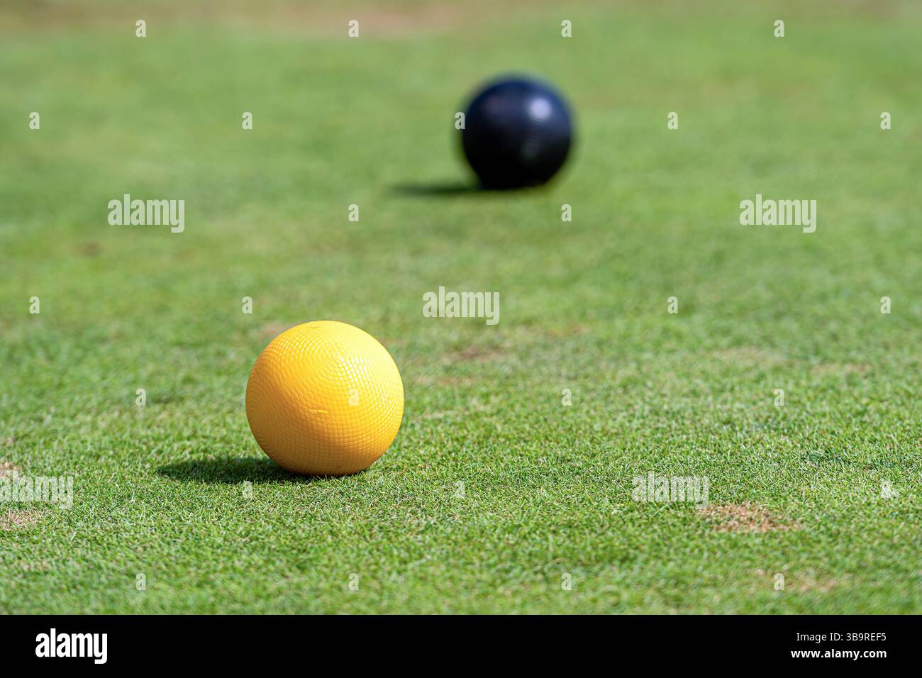 Colorful balls rest on a well-maintained lawn as players get ready for ...