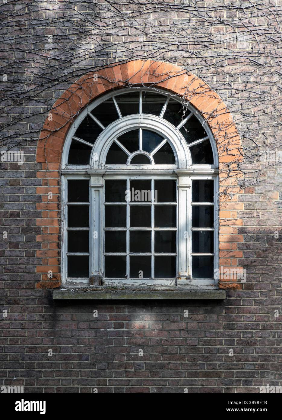 London, UK - May 08, 2025 - Semi oval mullioned frame window in a Red ...