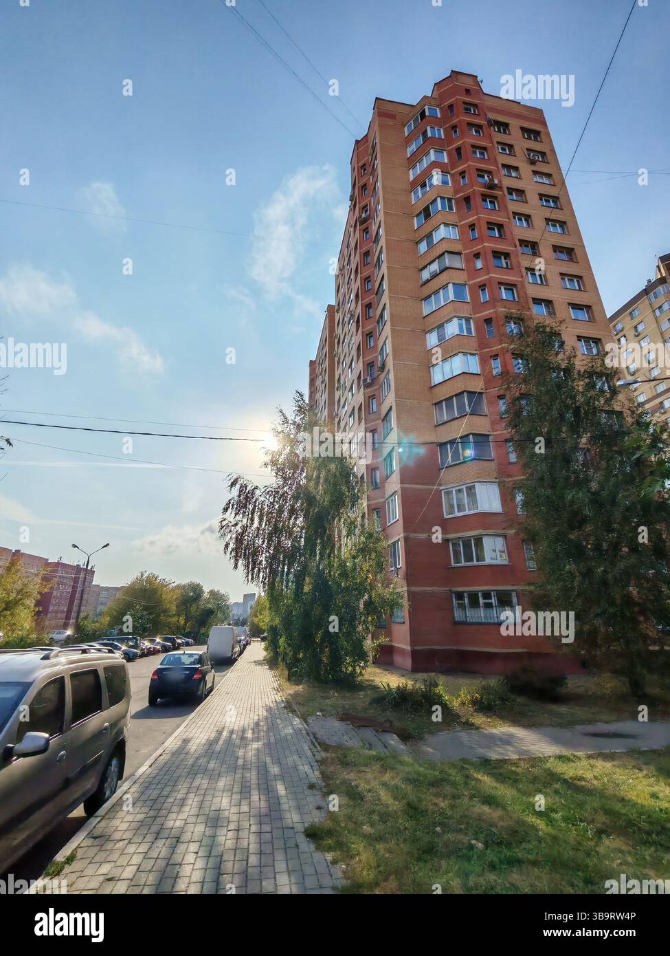 A modern apartment building with a red and beige brick facade, multiple ...