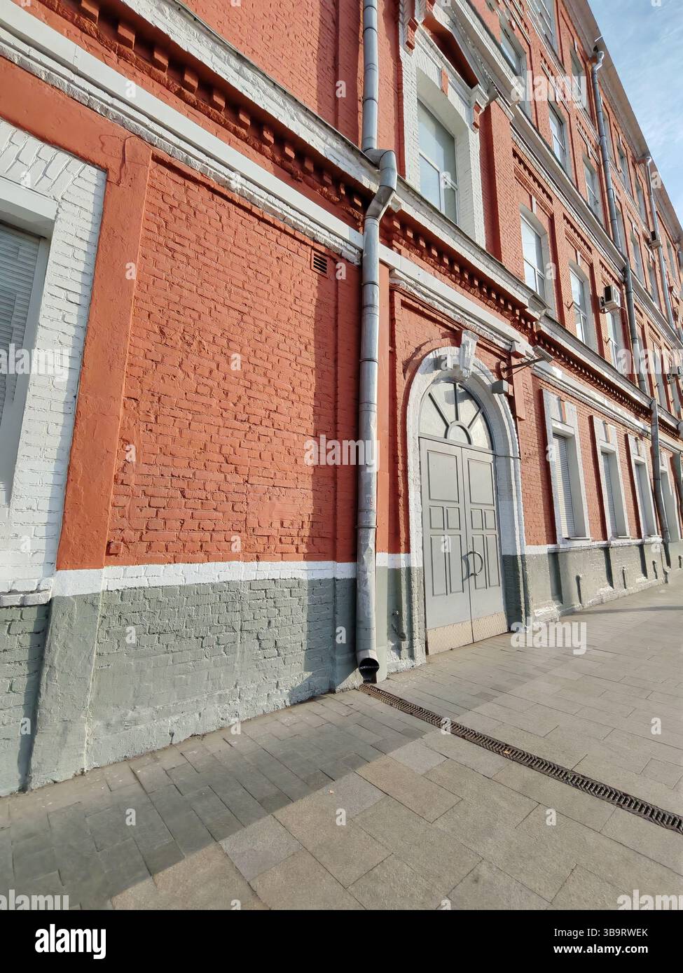 A vertical drainage pipe runs along a historic red brick wall with ...