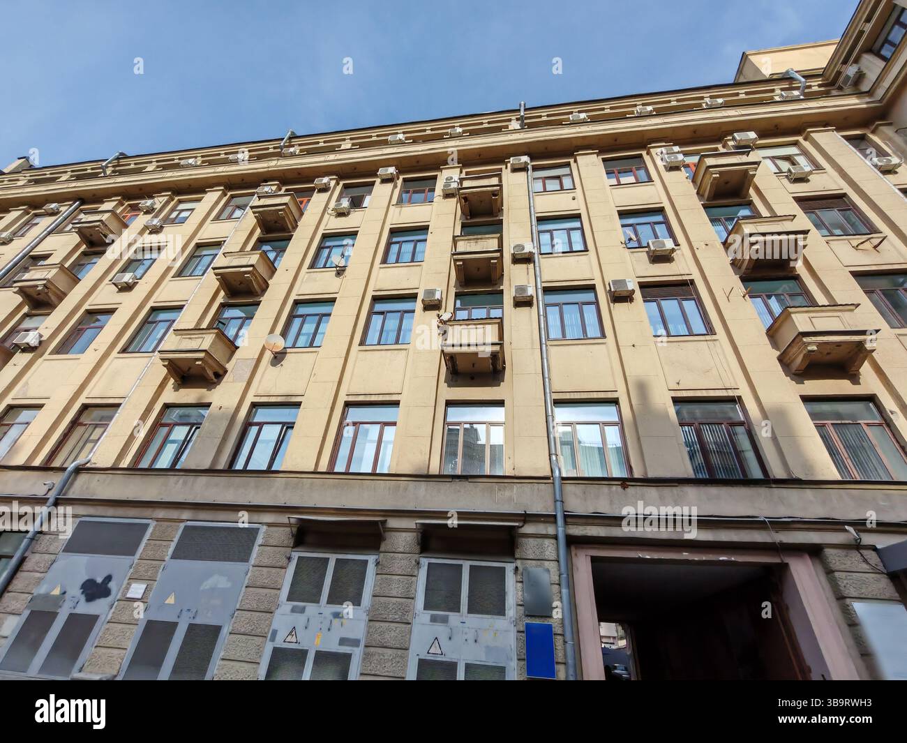 An upward view of a beige residential building with numerous windows ...