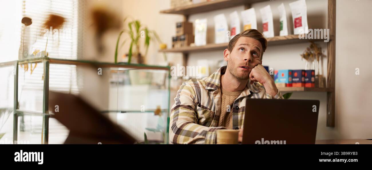 Portrait of stressed working man, sitting in cafe with laptop, business ...