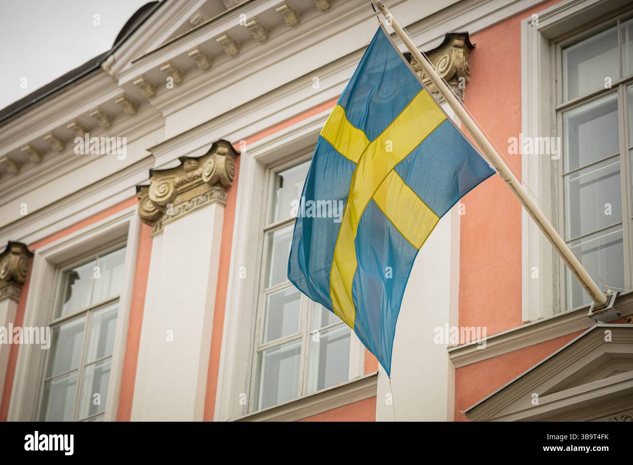 A Swedish flag waves in front of a historic building in Tallinn ...