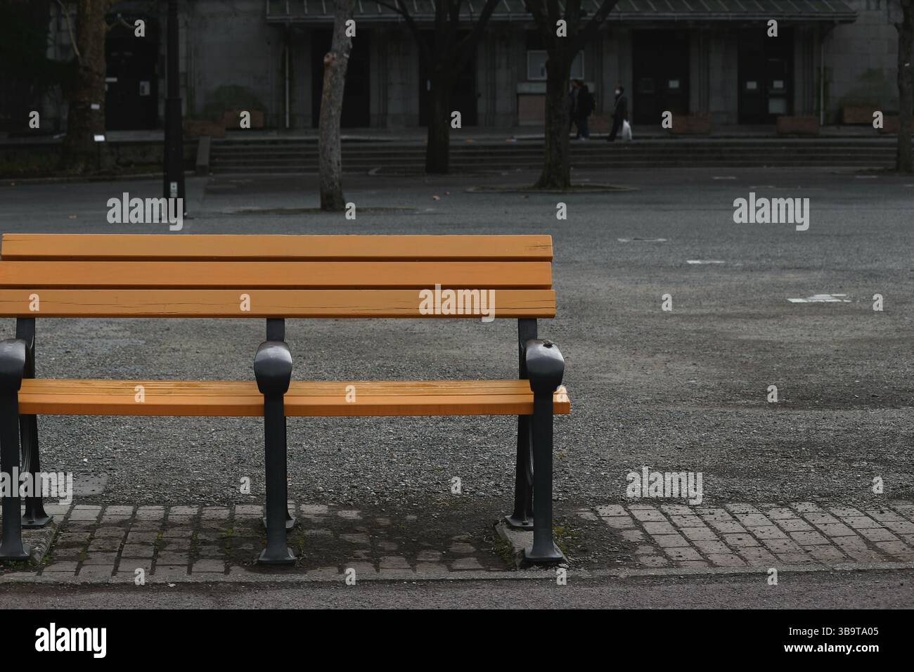 Everyday scenes in Japan An empty wooden bench in a city park square on ...