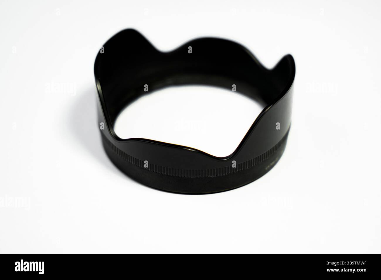 This image features a black camera lens hood isolated against a stark ...