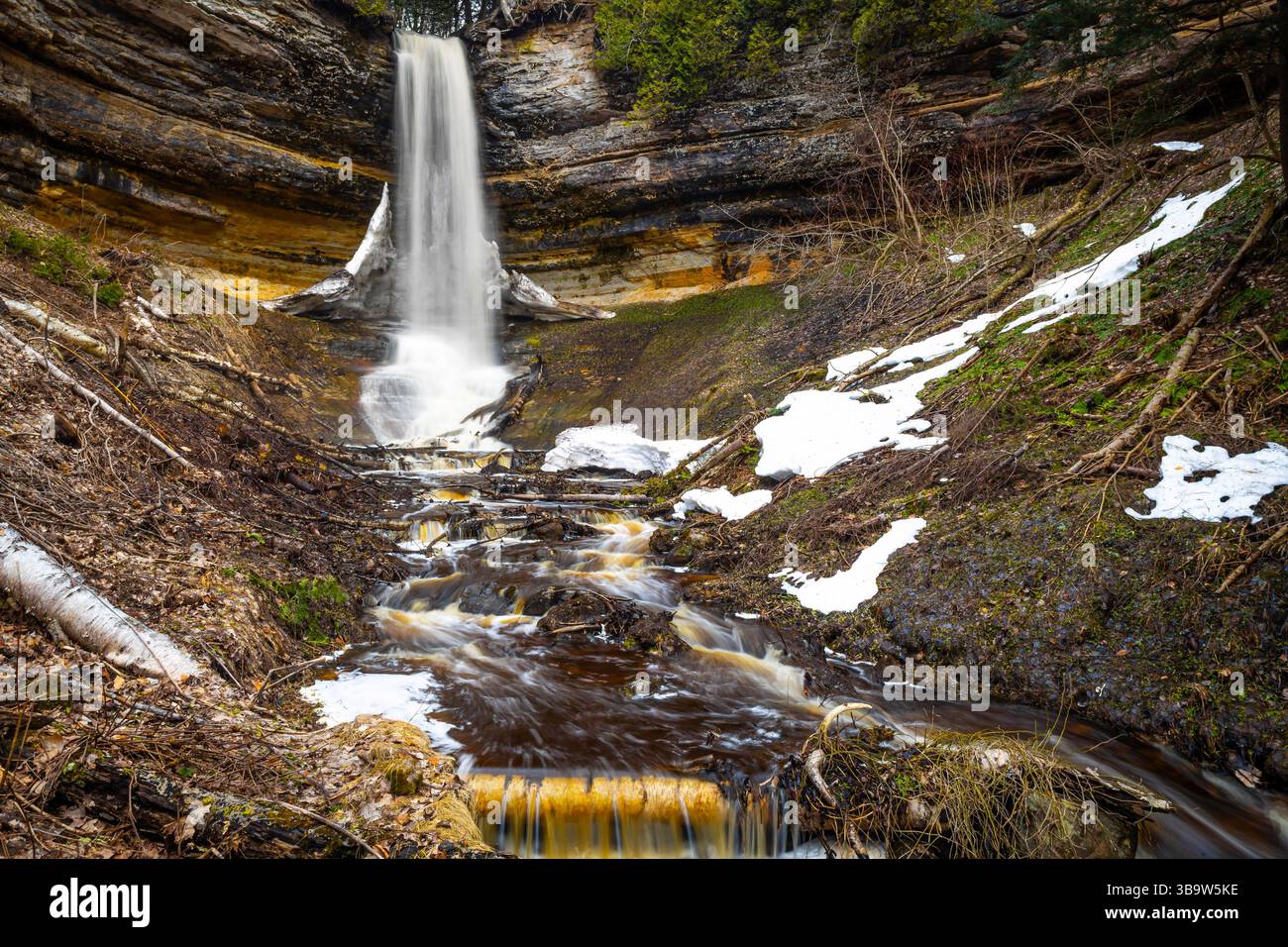 Photo of Munising Falls cascading down rock cliffs surrounded by forest ...