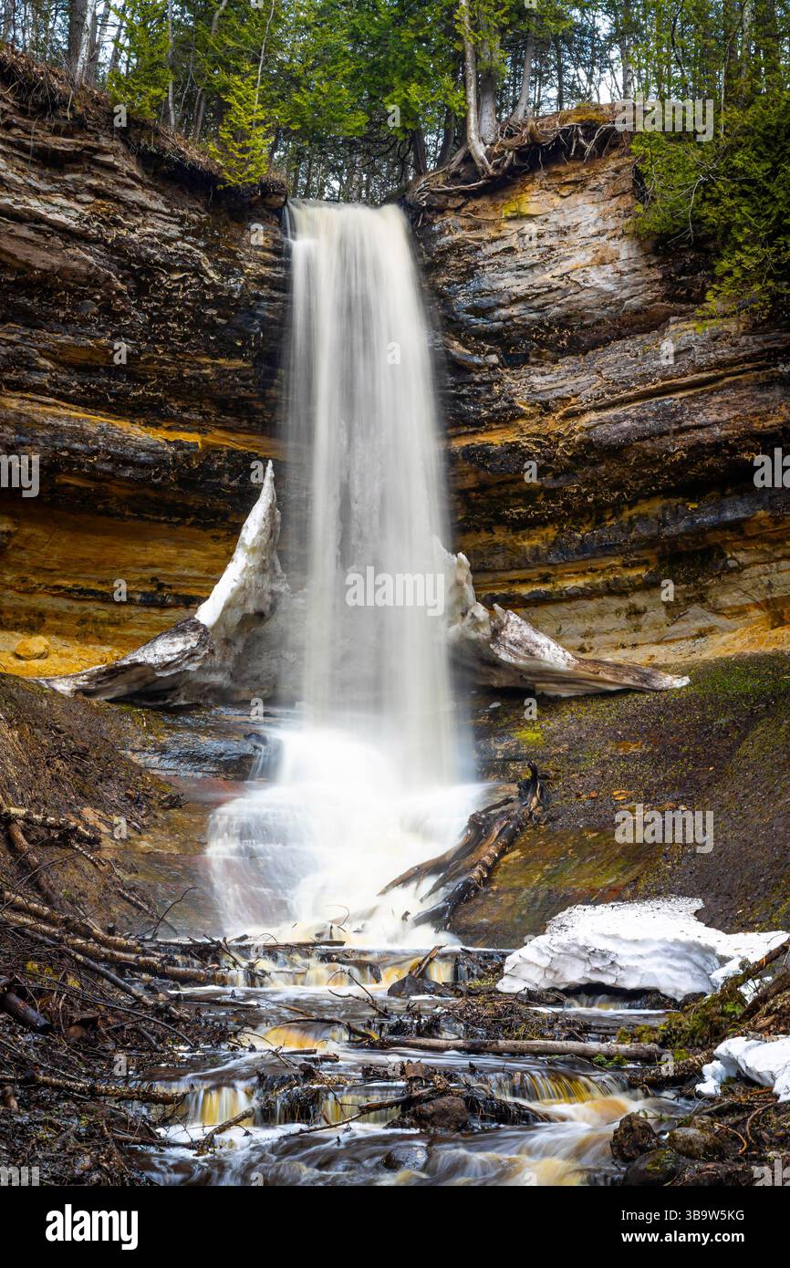 Photo of Munising Falls cascading down rock cliffs surrounded by forest ...