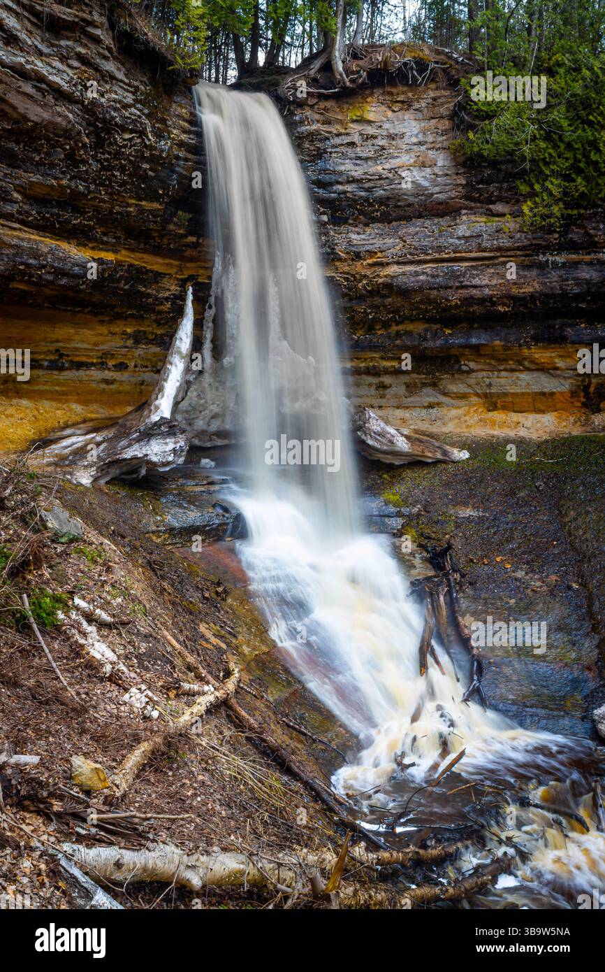 Photo of Munising Falls cascading down rock cliffs surrounded by forest ...