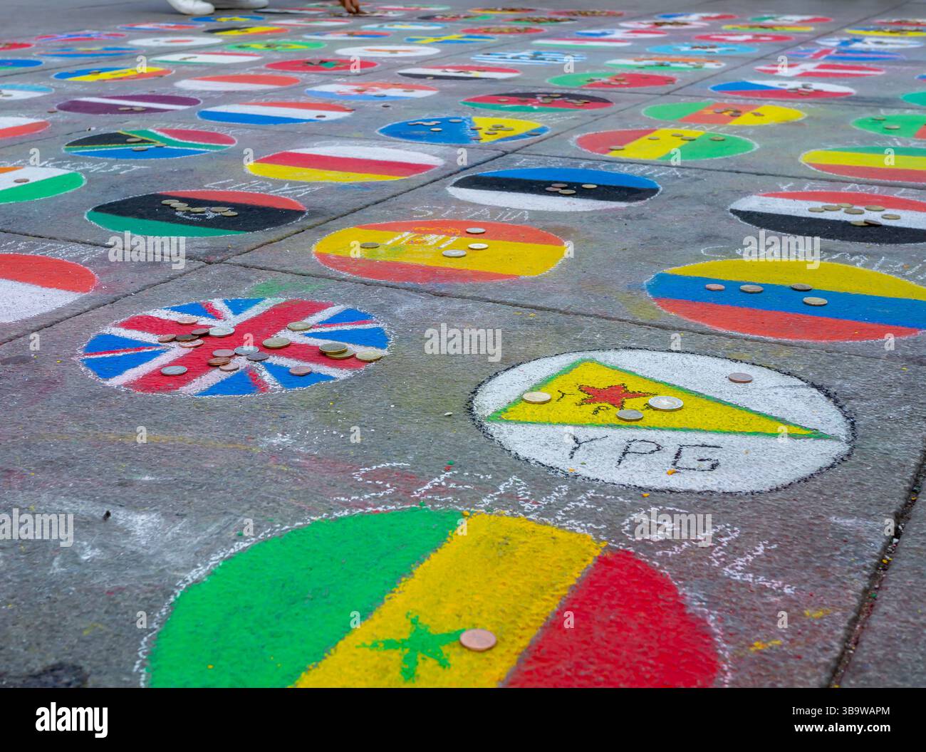 Chalk-painted world flags with coin donations on a Berlin sidewalk as ...