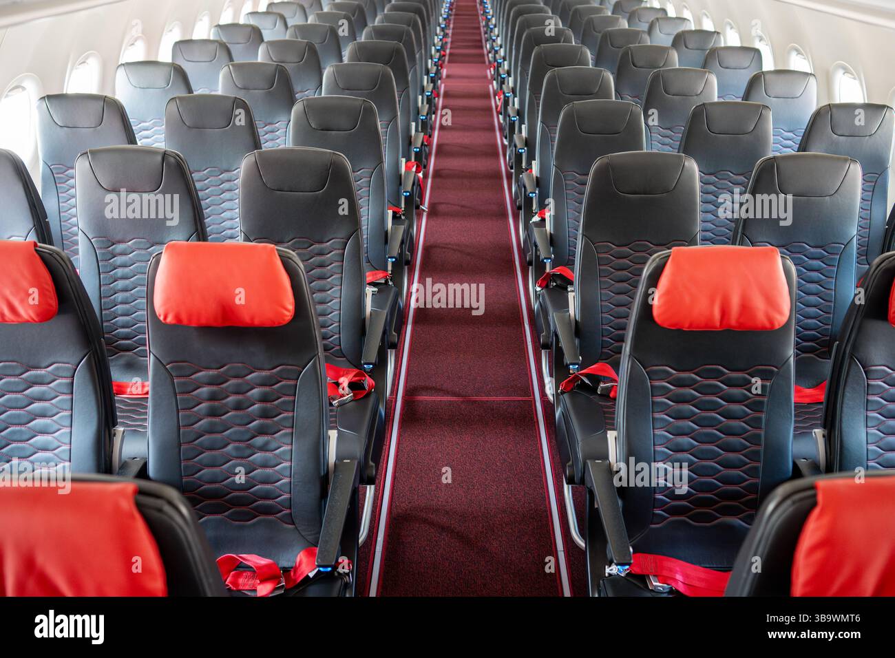 Empty interior of cabin of airplane with rows of black and red seats ...