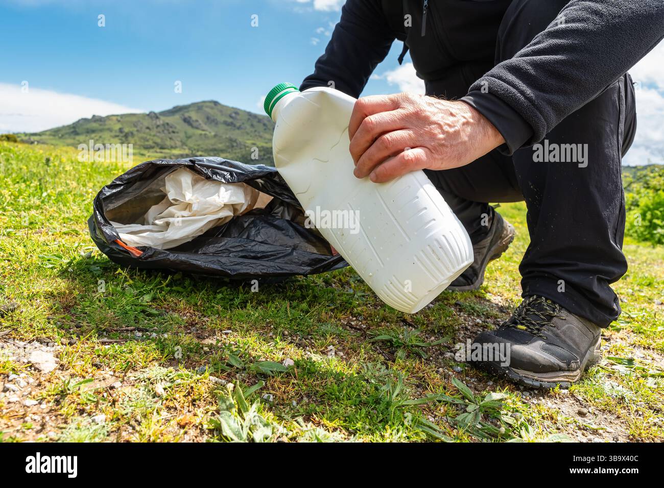 Volunteer man picking up garbage waste from the field and putting it in ...