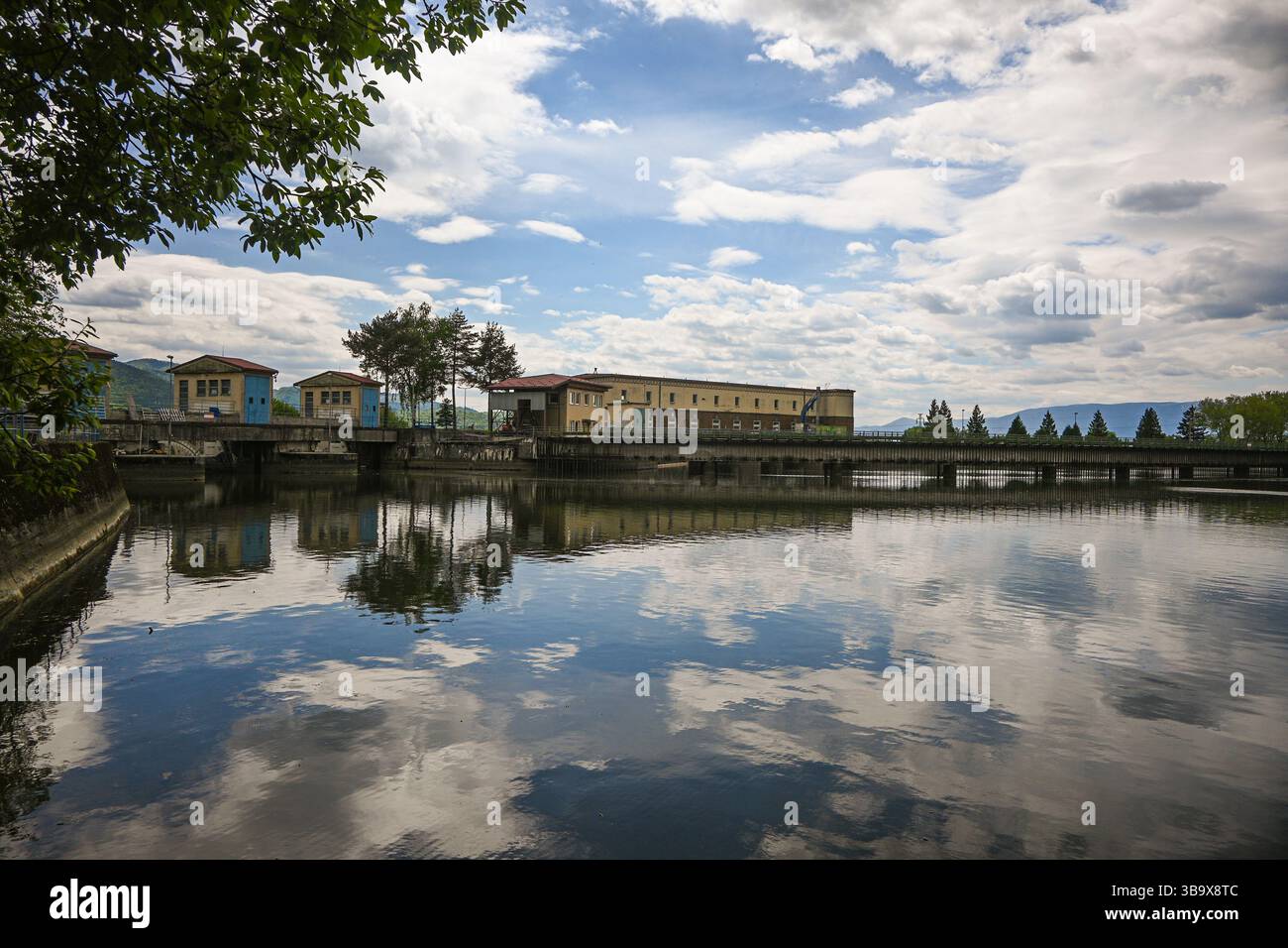 Hydroelectric power plant buildings and bridge reflected on the surface ...