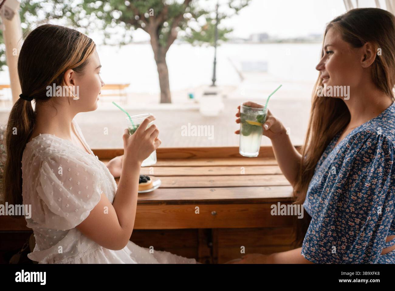 Friends Drinks Cafe: Two young women enjoy refreshing drinks at a ...