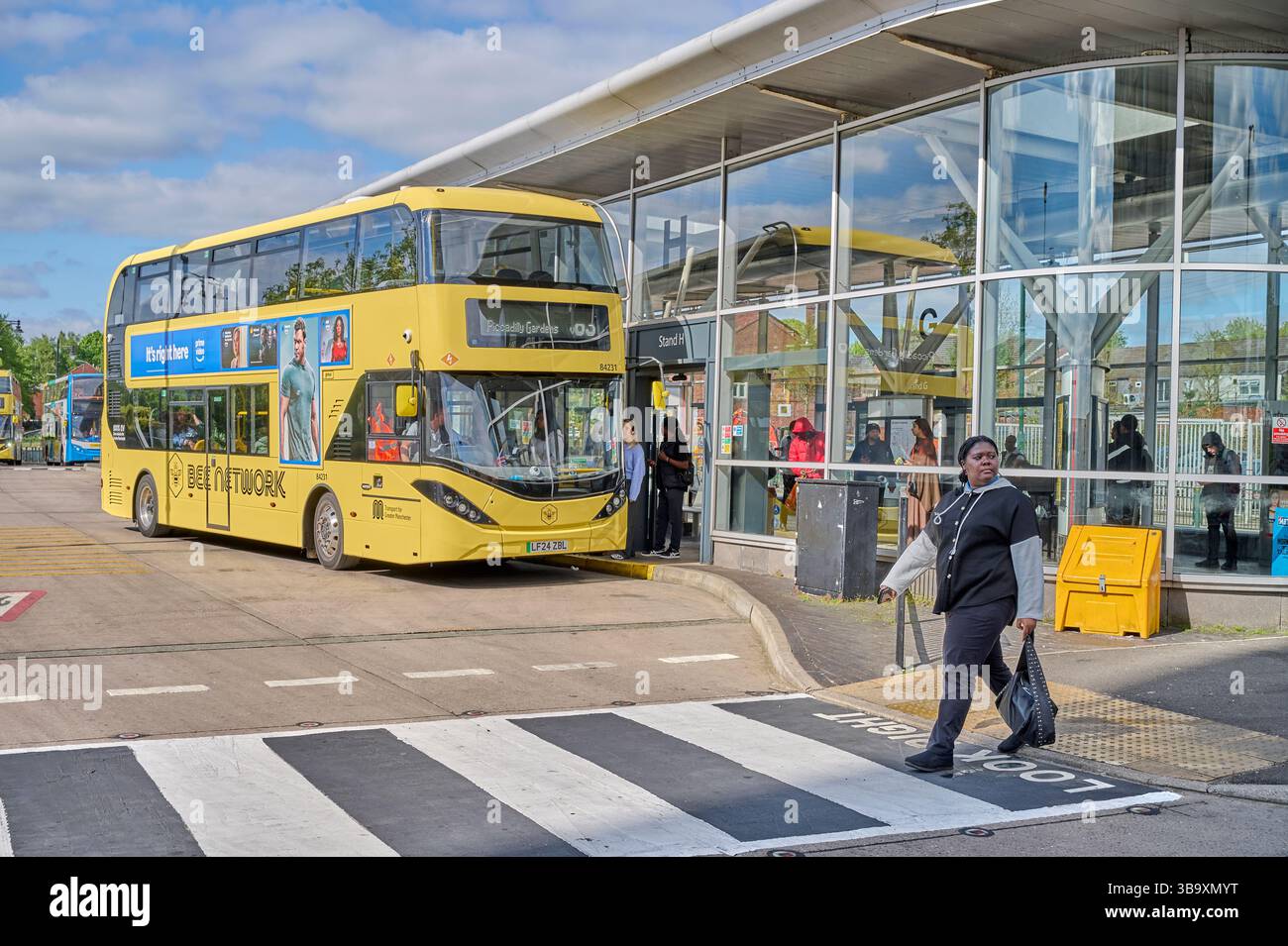 Woman crossing road infront of stationary bus at Oldham bus station ...