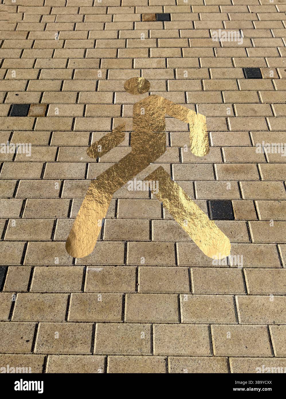 Golden pedestrian walking on a textured pavement, crossing the street ...