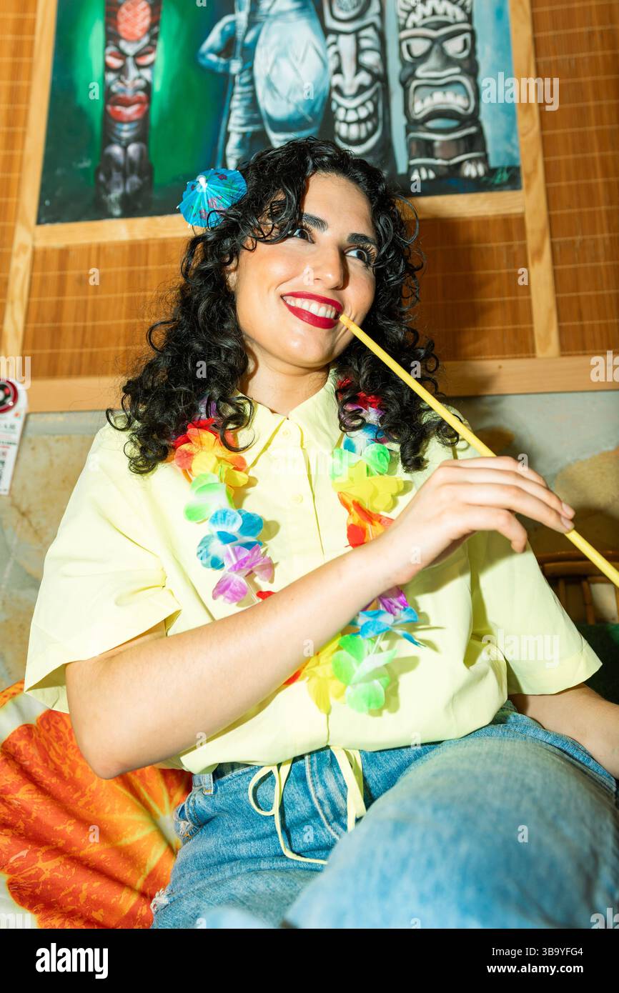 Smiling young woman wearing hawaiian lei and drinking a colorful ...