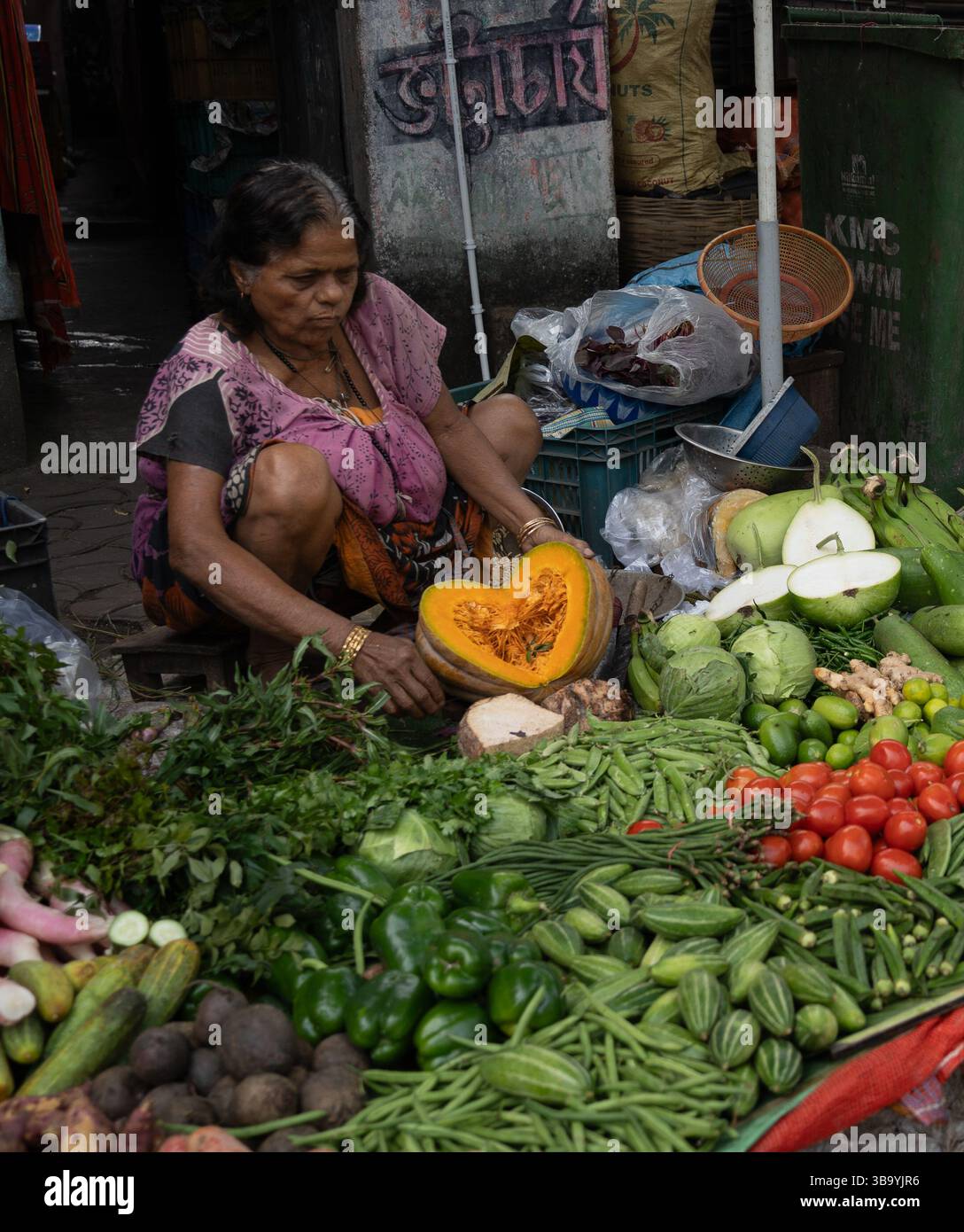 An Indian female vegetable seller sits at her street market stall ...