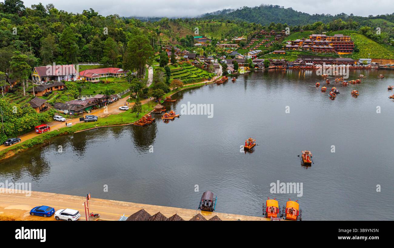 Aerial view of tranquil lakeside village nestled in lush, mist-covered ...