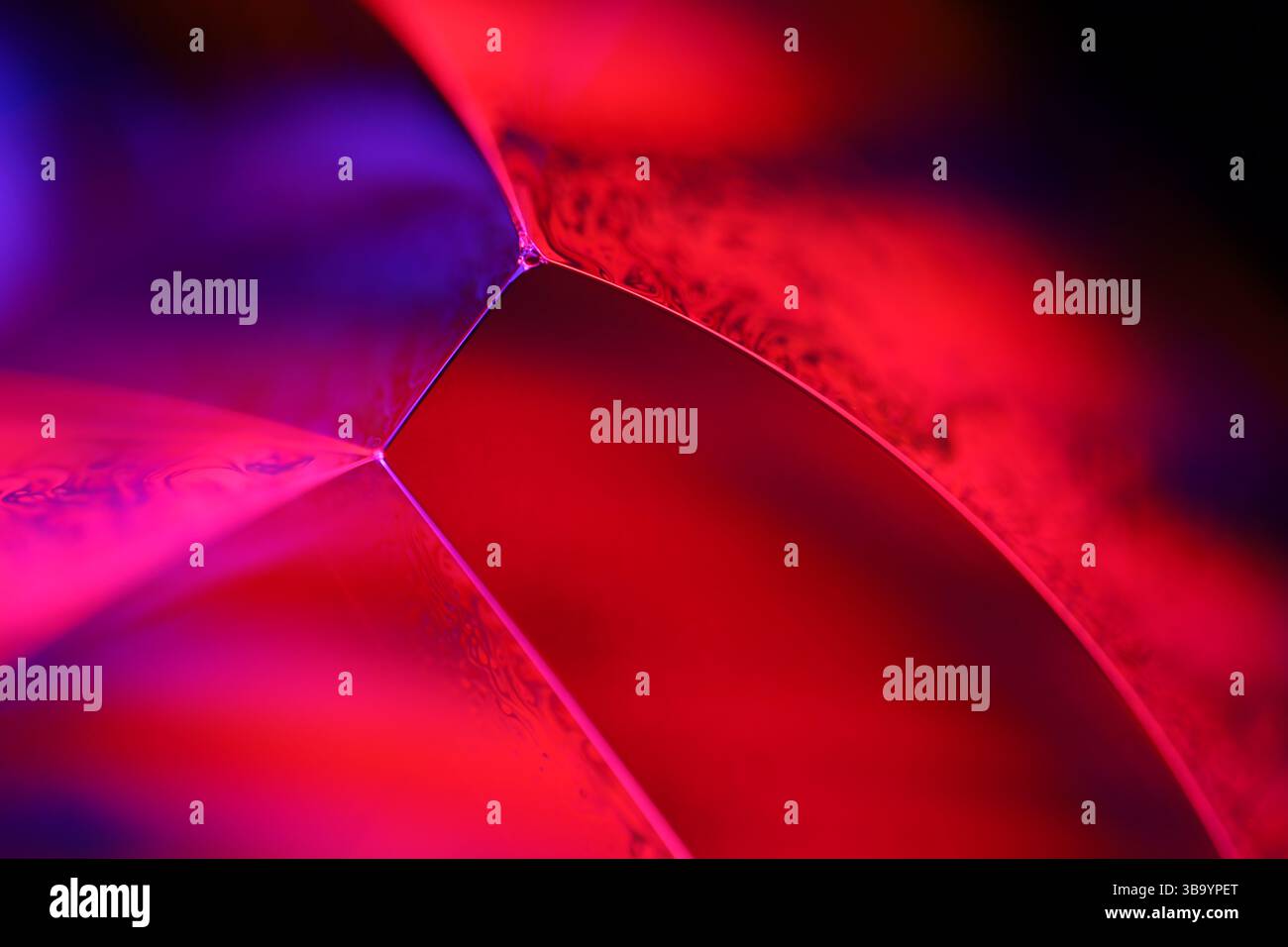 Red and purple fluid reflections on black background, liquid surface ...