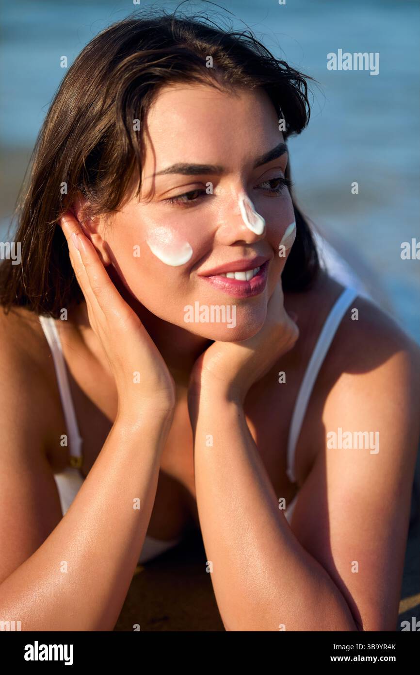 Young pretty woman applying sun cream and touch own face. Skincare ...