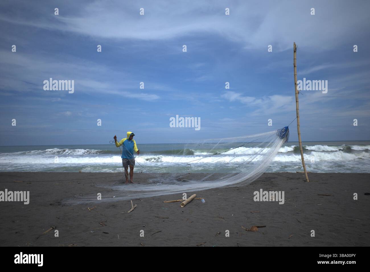 A fisherman prepares a net to catch fish at Congot Beach, Kulon Progo ...
