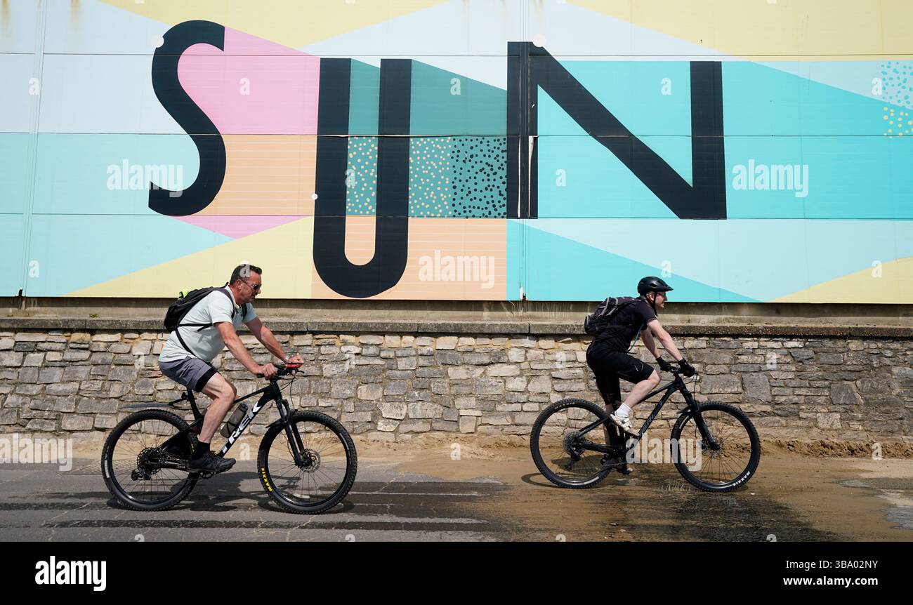 People cycle along the sea front on Boscombe Beach in Dorset. Heavy showers will hit parts of ...