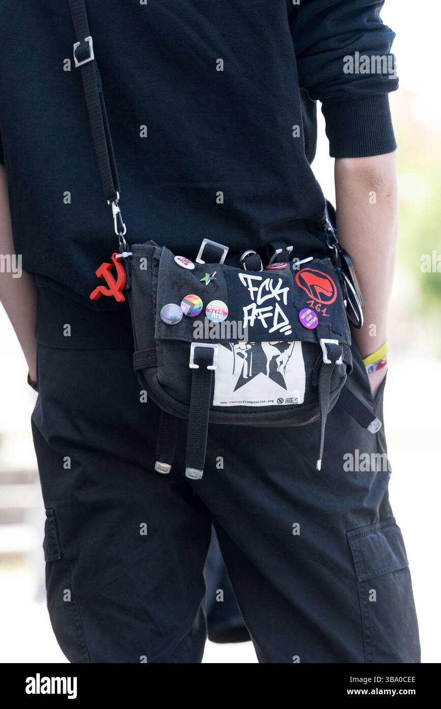 11 May 2025, Bavaria, Munich: A young man carries a shoulder bag with ...