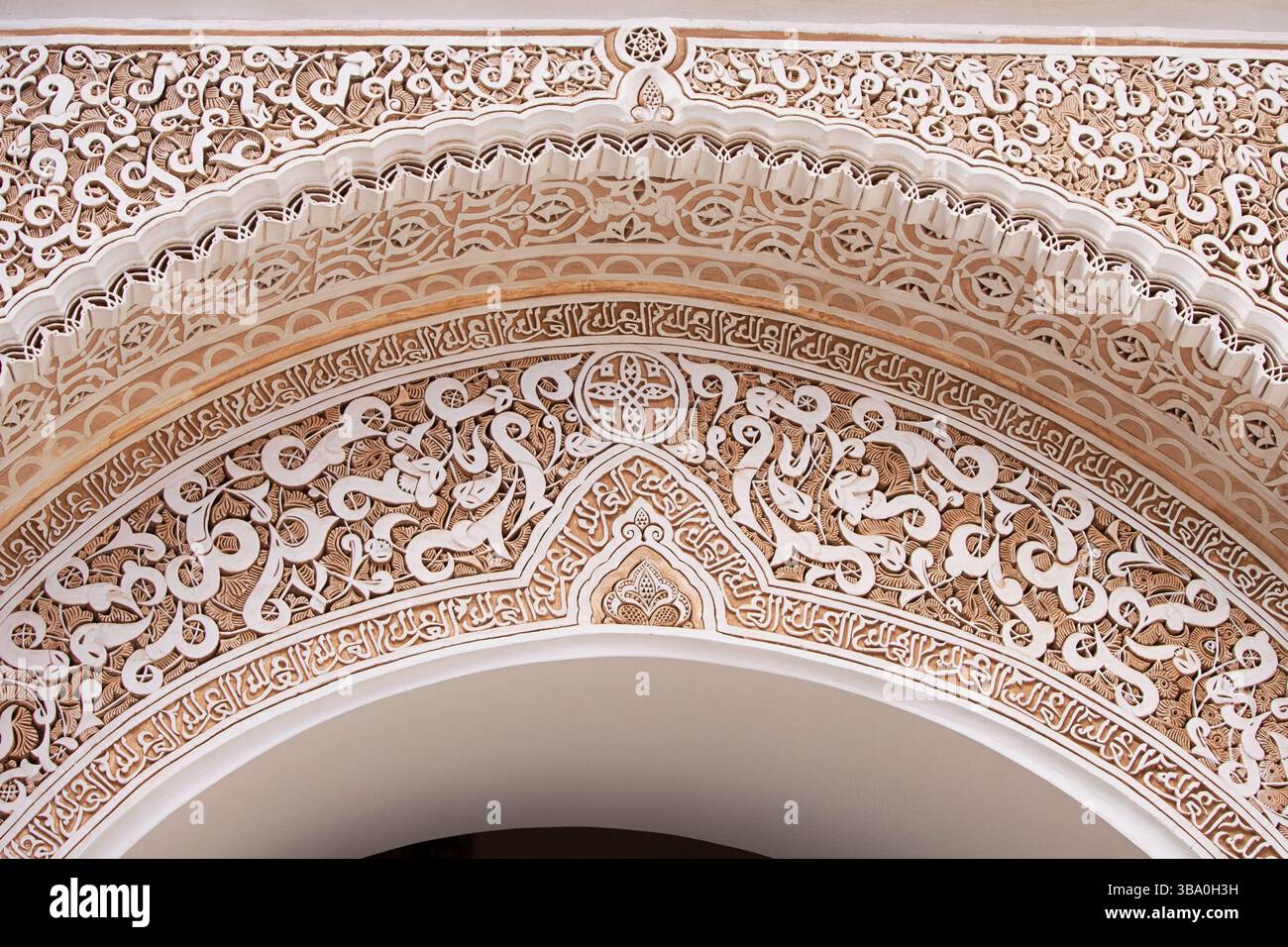 Beautifully preserved moorish arch displaying intricate islamic calligraphy and arabesque stucco ...