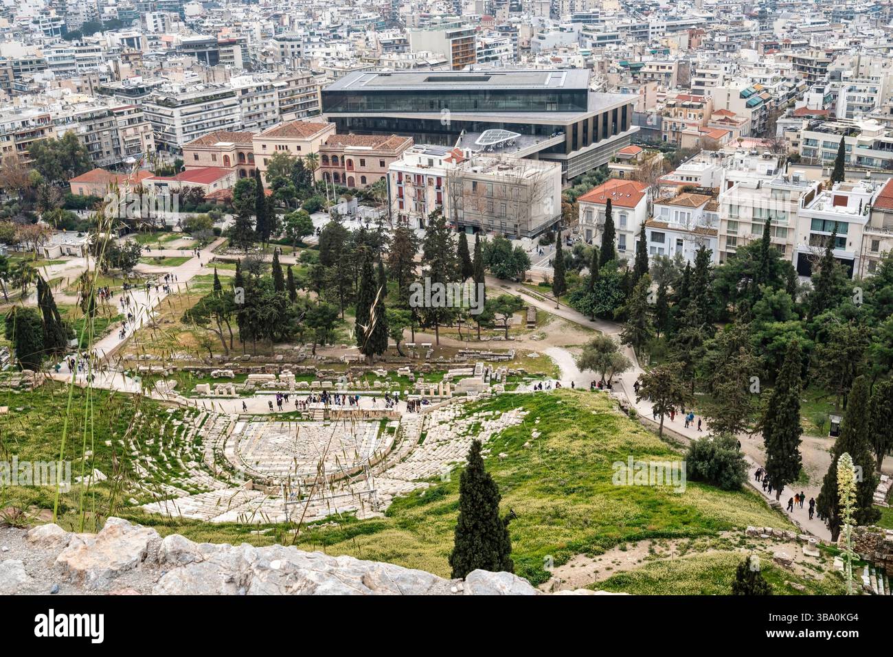Elevated view of the ancient Theatre of Dionysus nestled below the Acropolis, with the modern ...