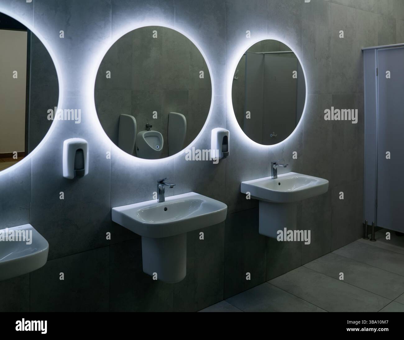 Interior of modern public toilet with white sinks and led lights Stock ...
