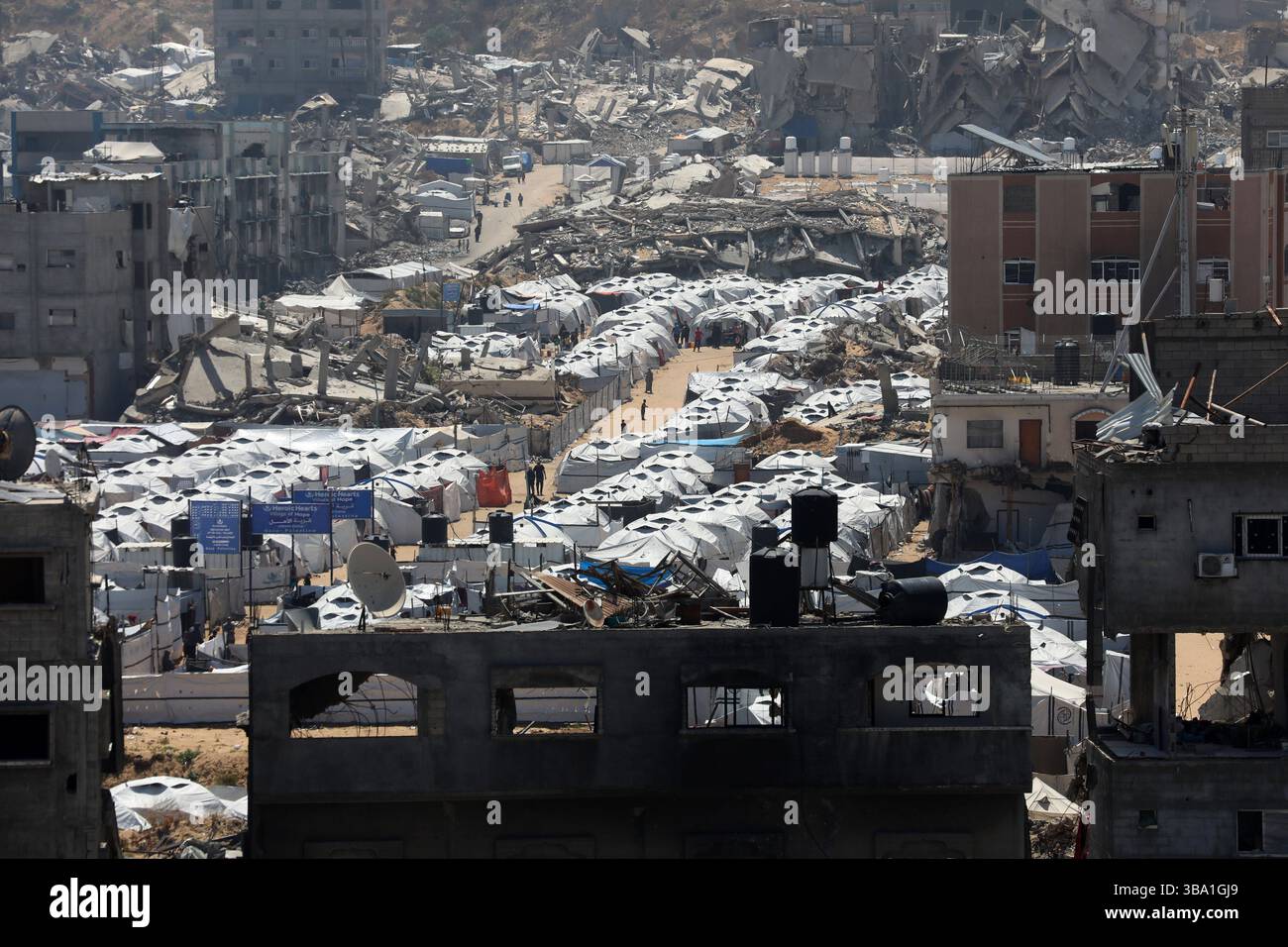Displaced Palestinians taking refuge in makeshift tents and heavily ...