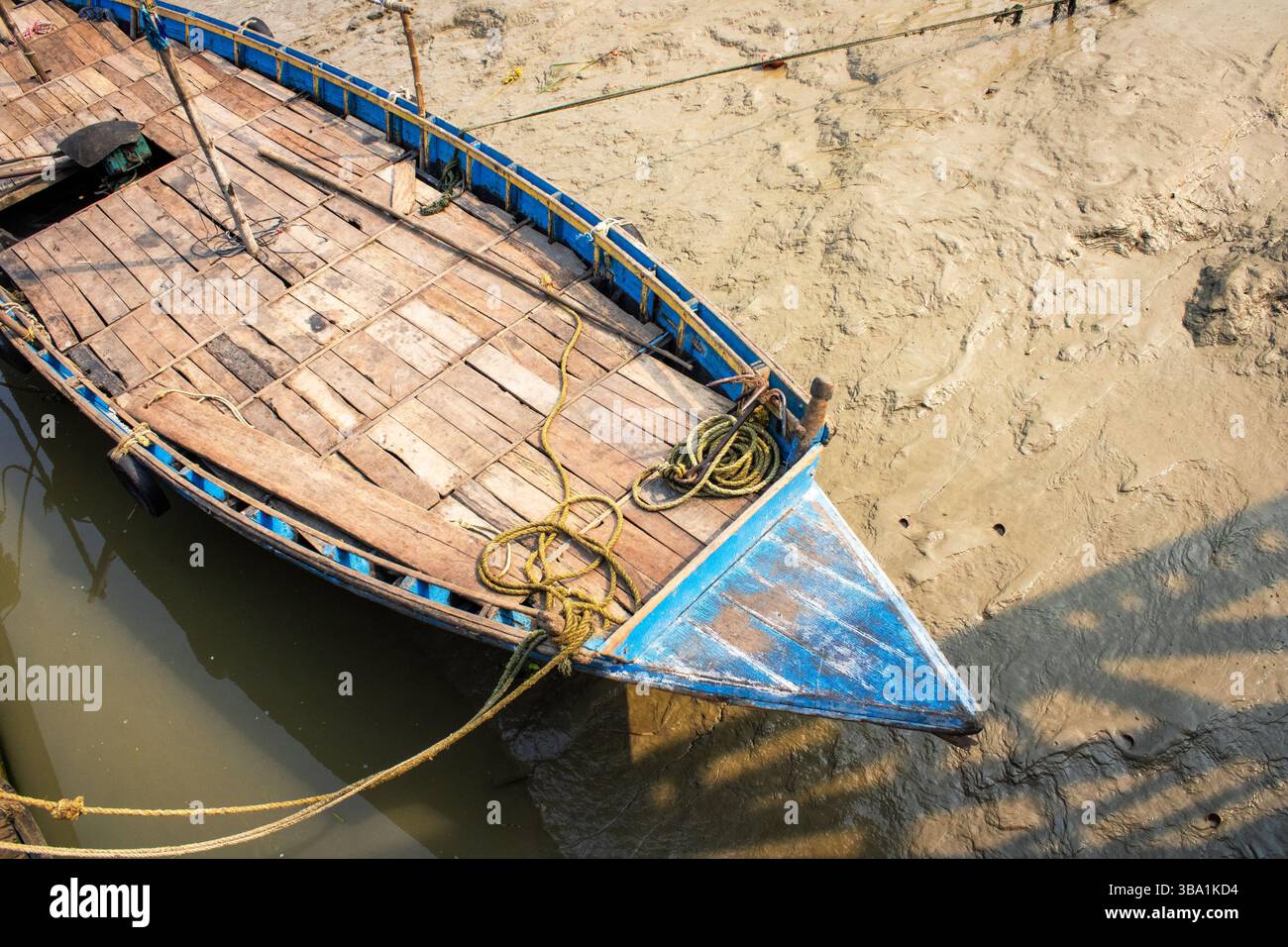 Wooden boat with vibrant blue paint positioned on a drying muddy ...