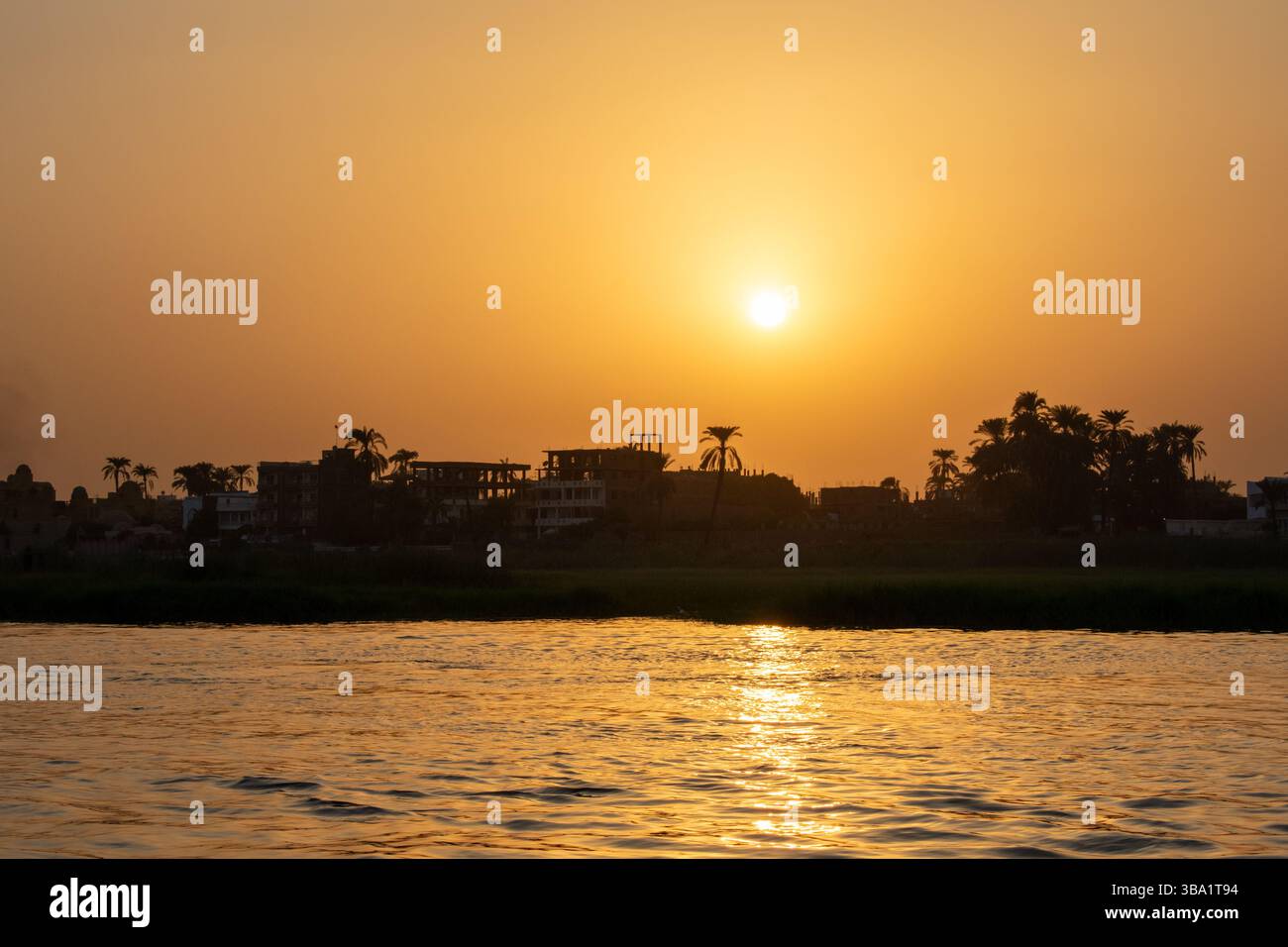 Beautiful sunset over Nile River in Luxor, Egypt. Buildings and palm ...