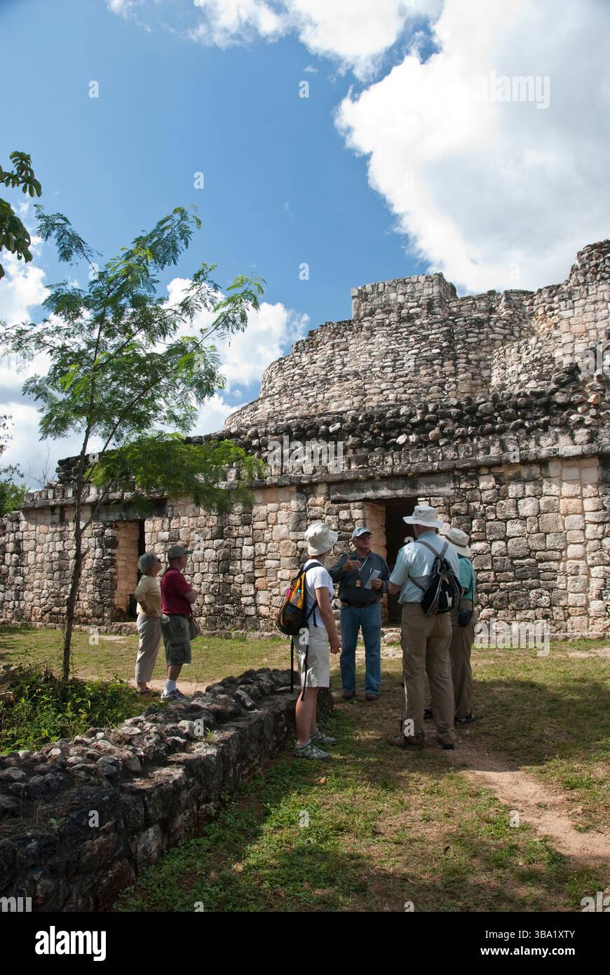 A tour group visits the Oval Palace, at the Mayan archaeological site ...