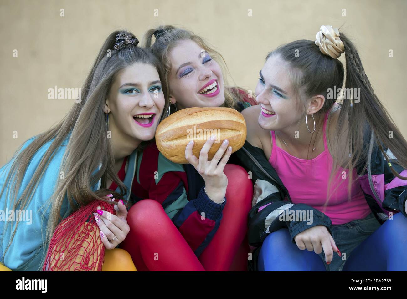 Three pretty girls dressed in the style of the nineties are sitting on ...