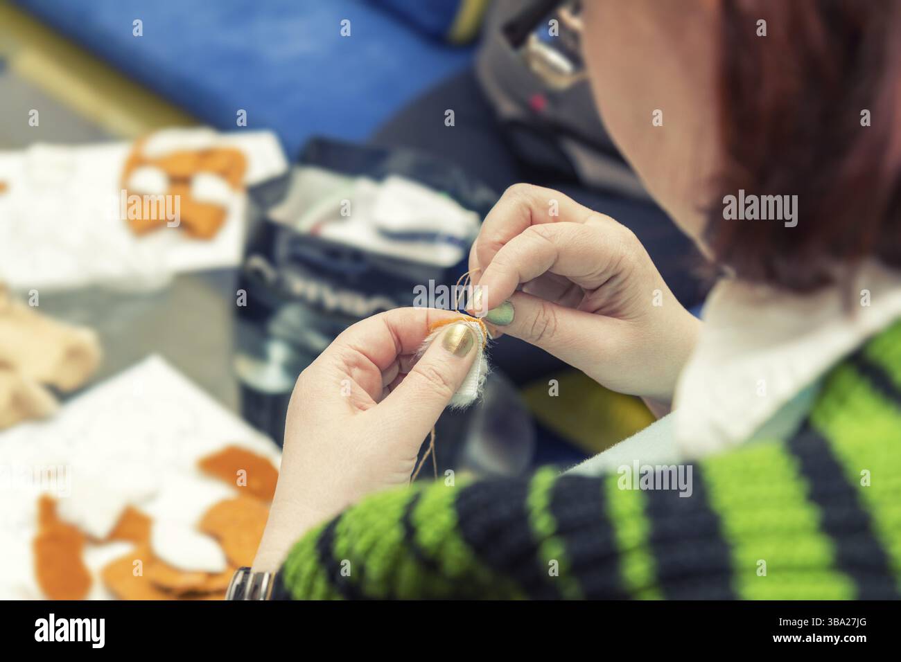 Woman hands stitches synthetic fur pieces. Close up. Coloring and ...