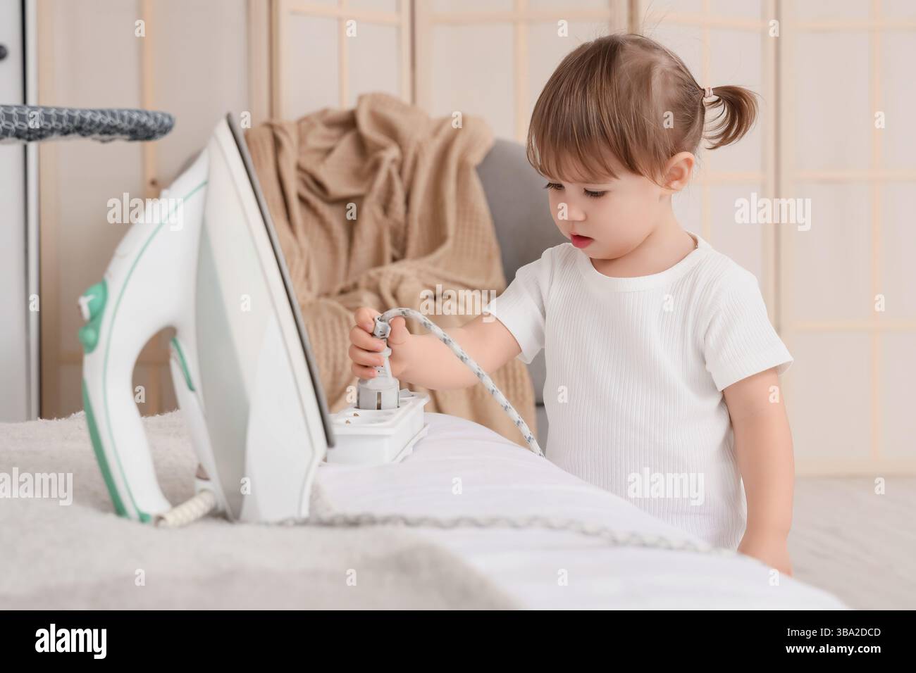 Cute little girl plugging electric iron into extension cord in bedroom ...