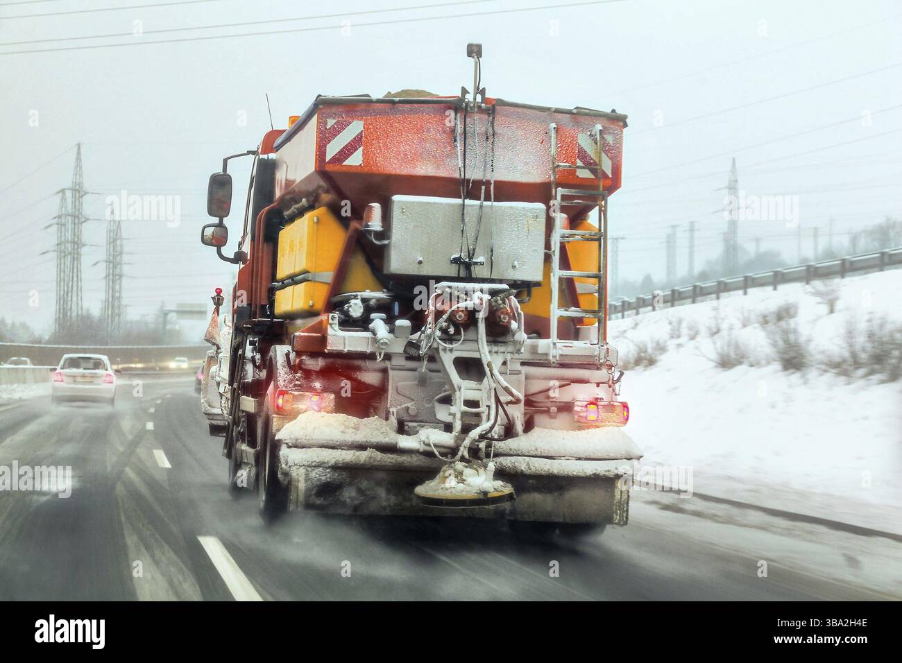 Bright orange gritter maintenance truck spreading deicing salt and sand ...
