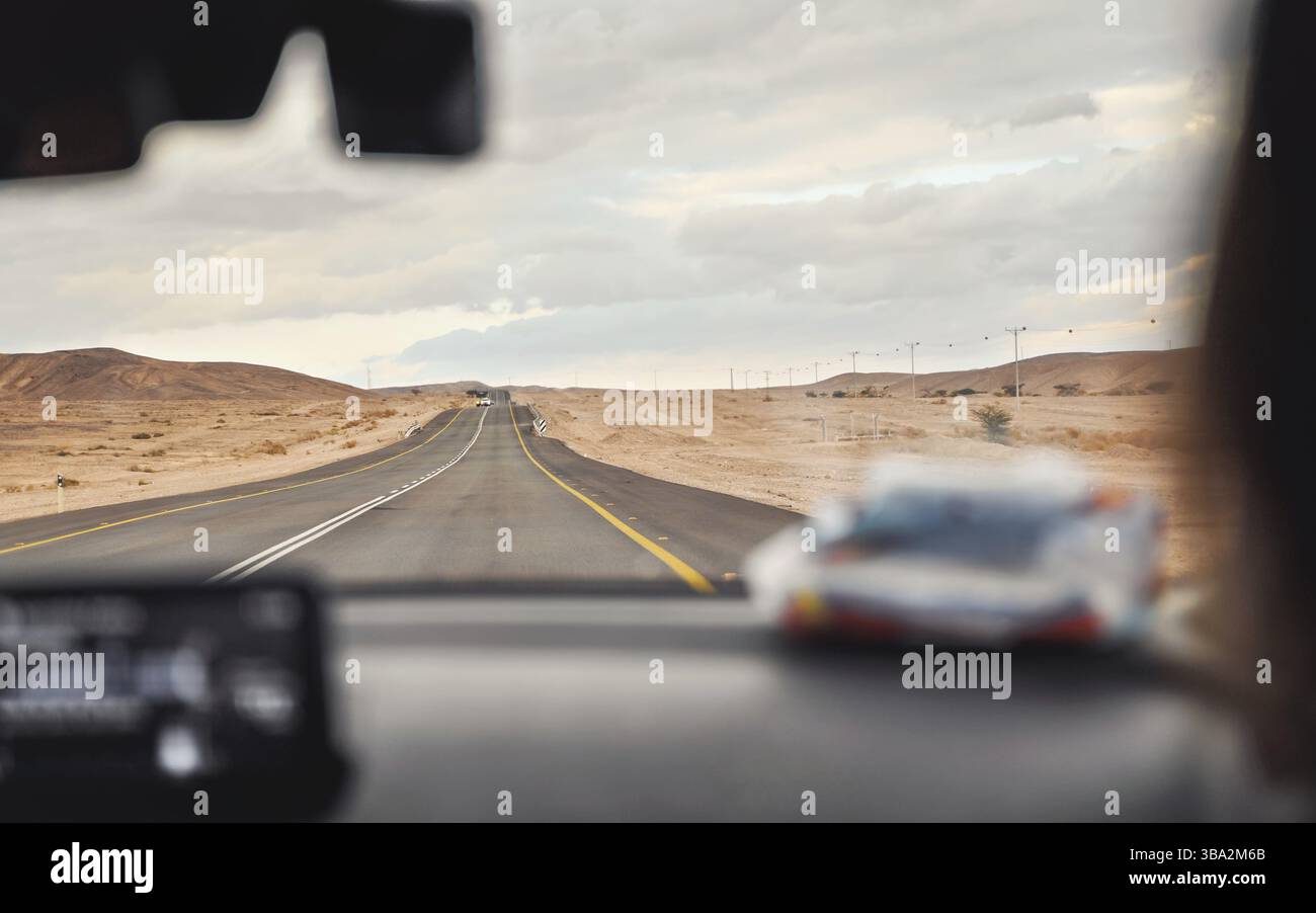 Car driving through desert landscape on overcast day, view from ...