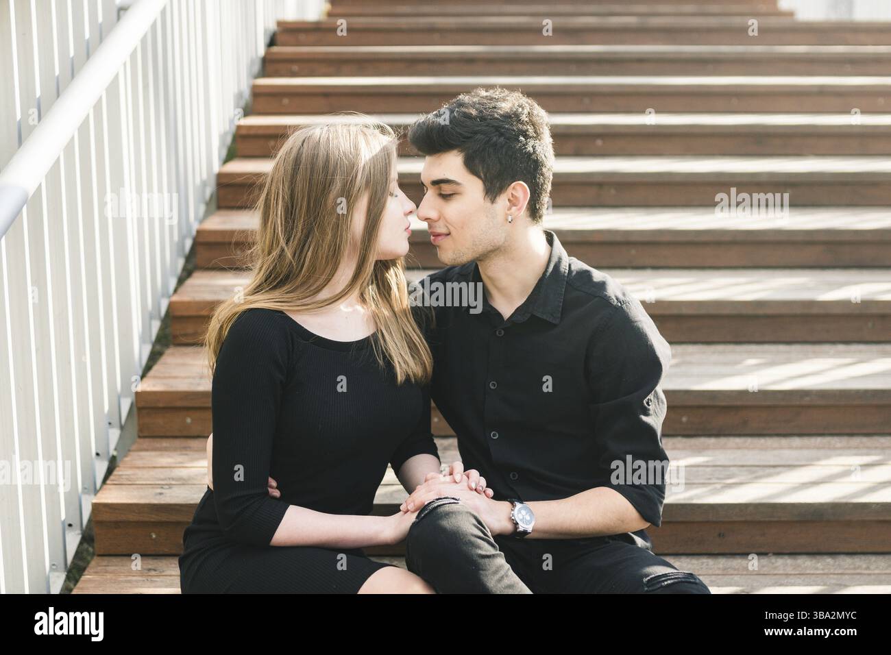 Beautiful young multiracial couple, student couple in love, sit wooden ...