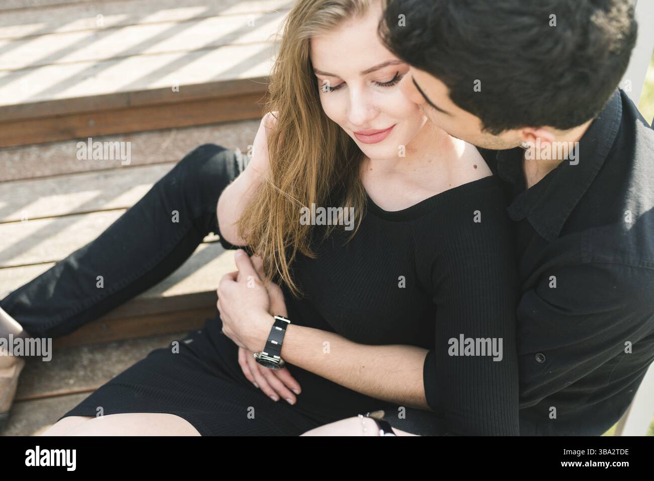 Beautiful young multiracial couple, student couple in love, sit wooden ...