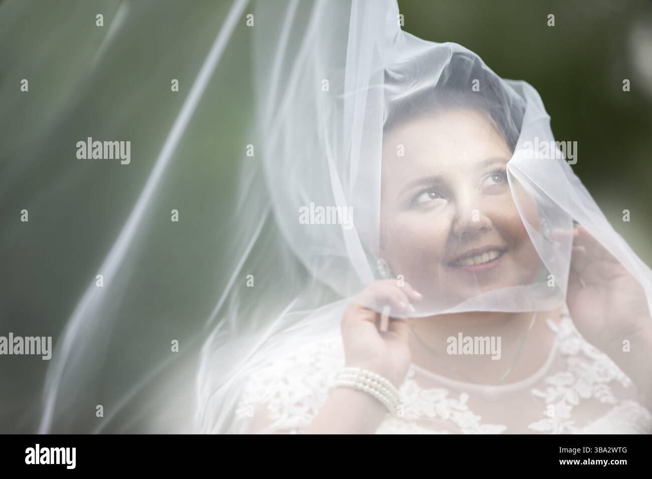 The fat bride hid in a wedding veil against the backdrop of nature ...