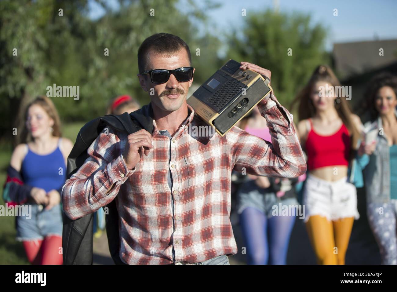 Funny man with a cassette recorder in front of a group of girls. People ...