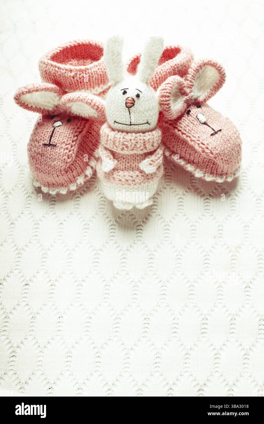 Knitted pink baby booties with rabbit muzzle over textile background ...