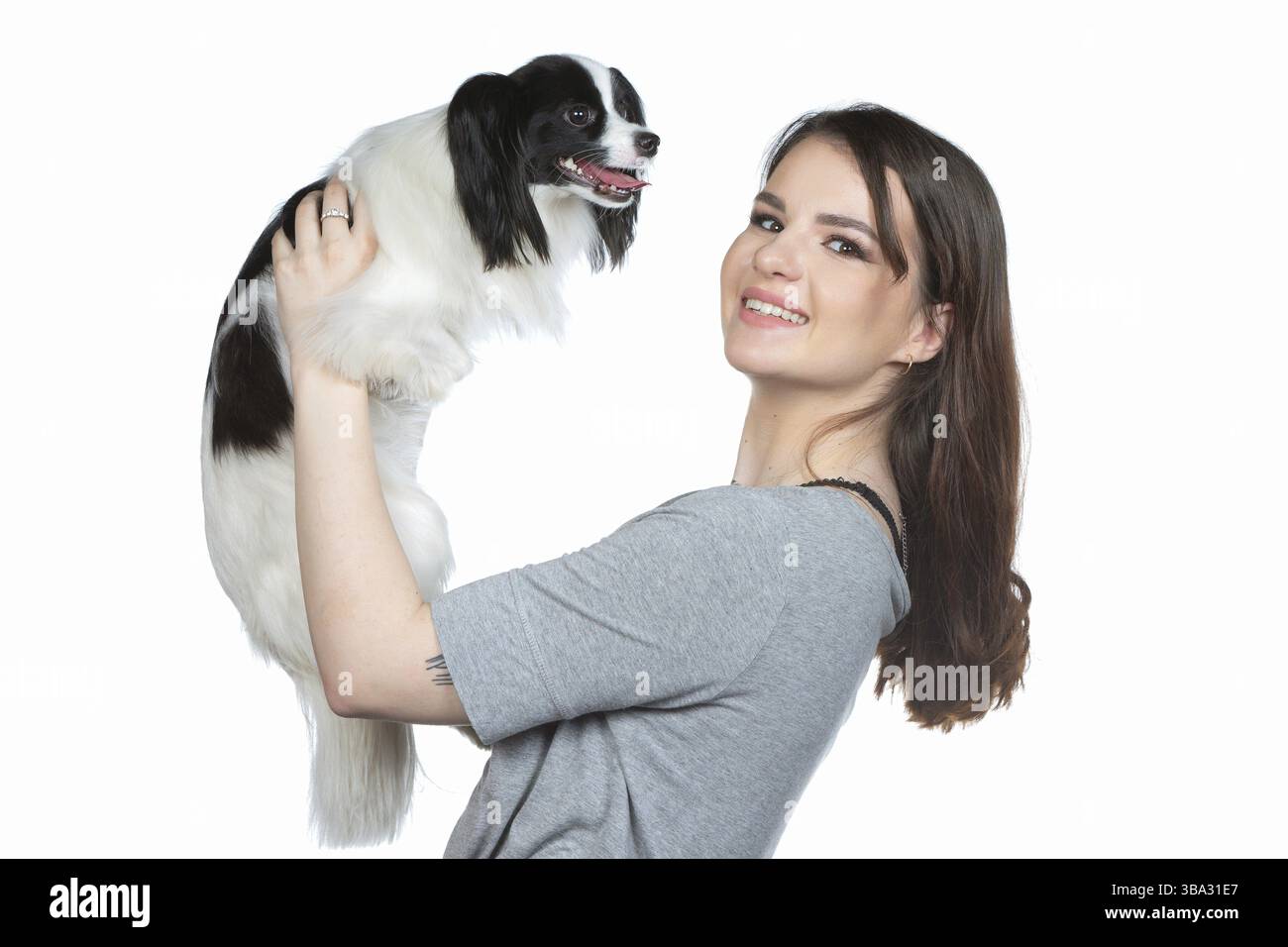 A cute young woman is hugging her papillon puppy. Love between owner ...