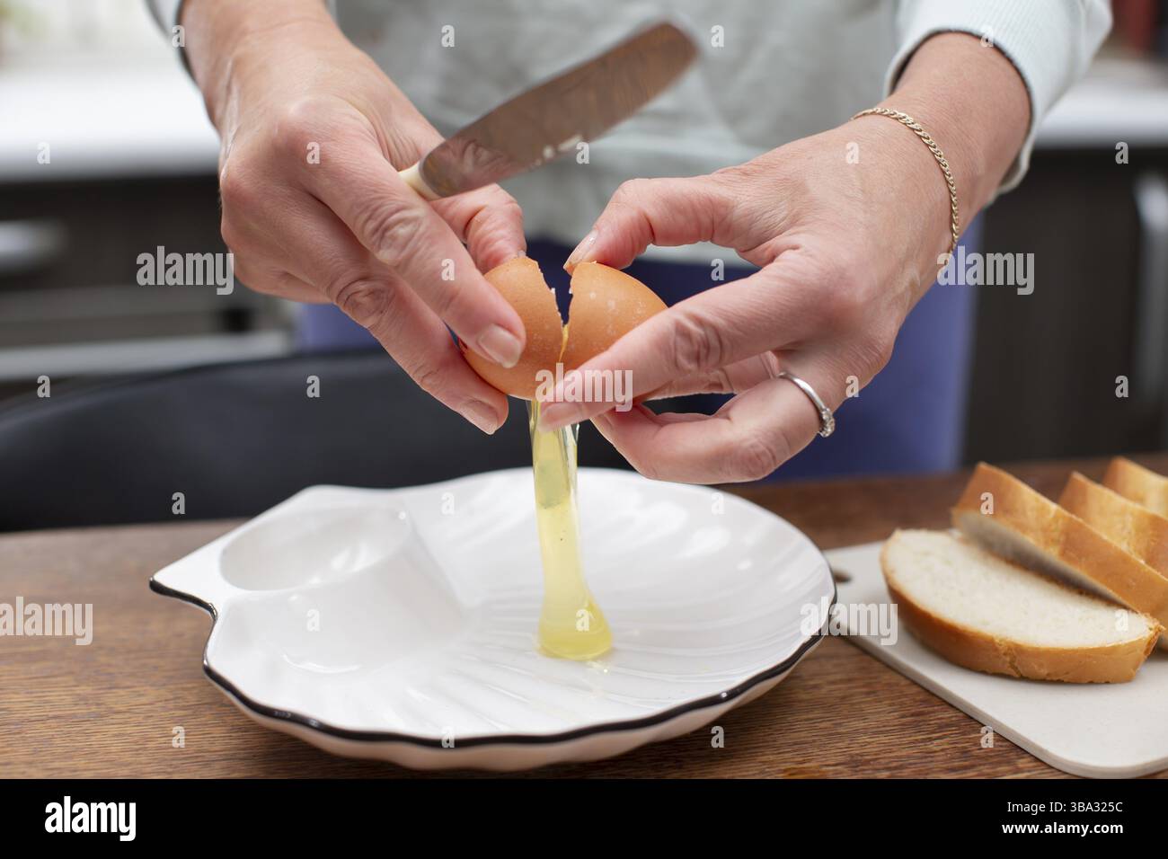 The hands broke the egg and it flows into the plate. Cook breakfast ...