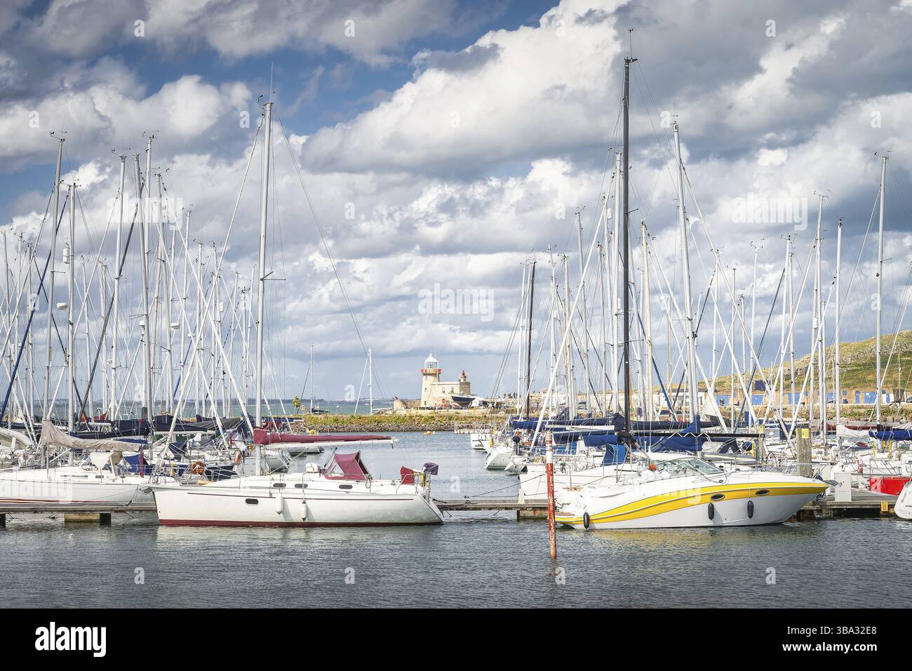 Howth lighthouse seen through masts of sailboats, yachts and motorboats ...